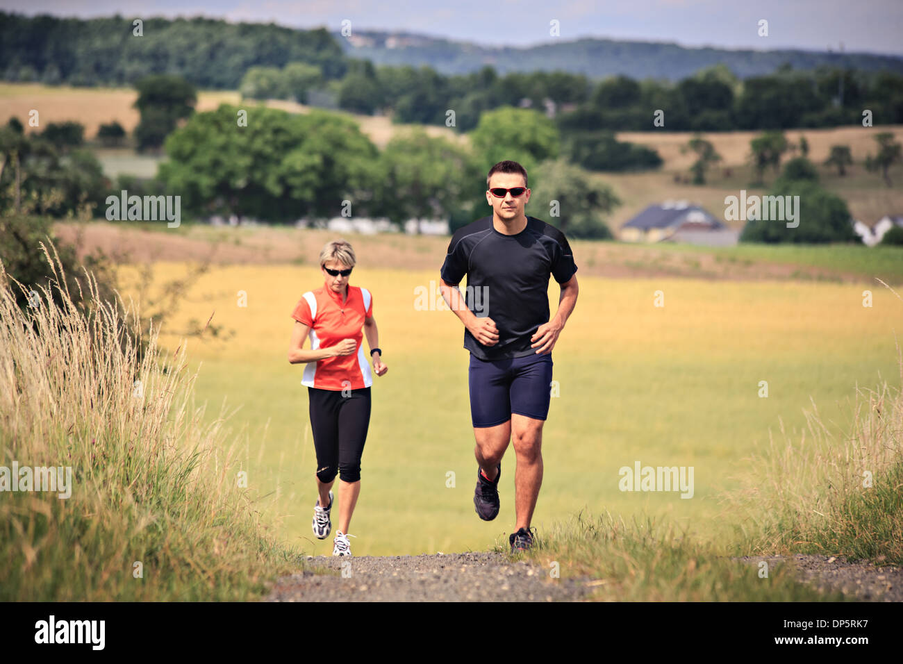 people jogging on the road in front of rural landscape Stock Photo - Alamy