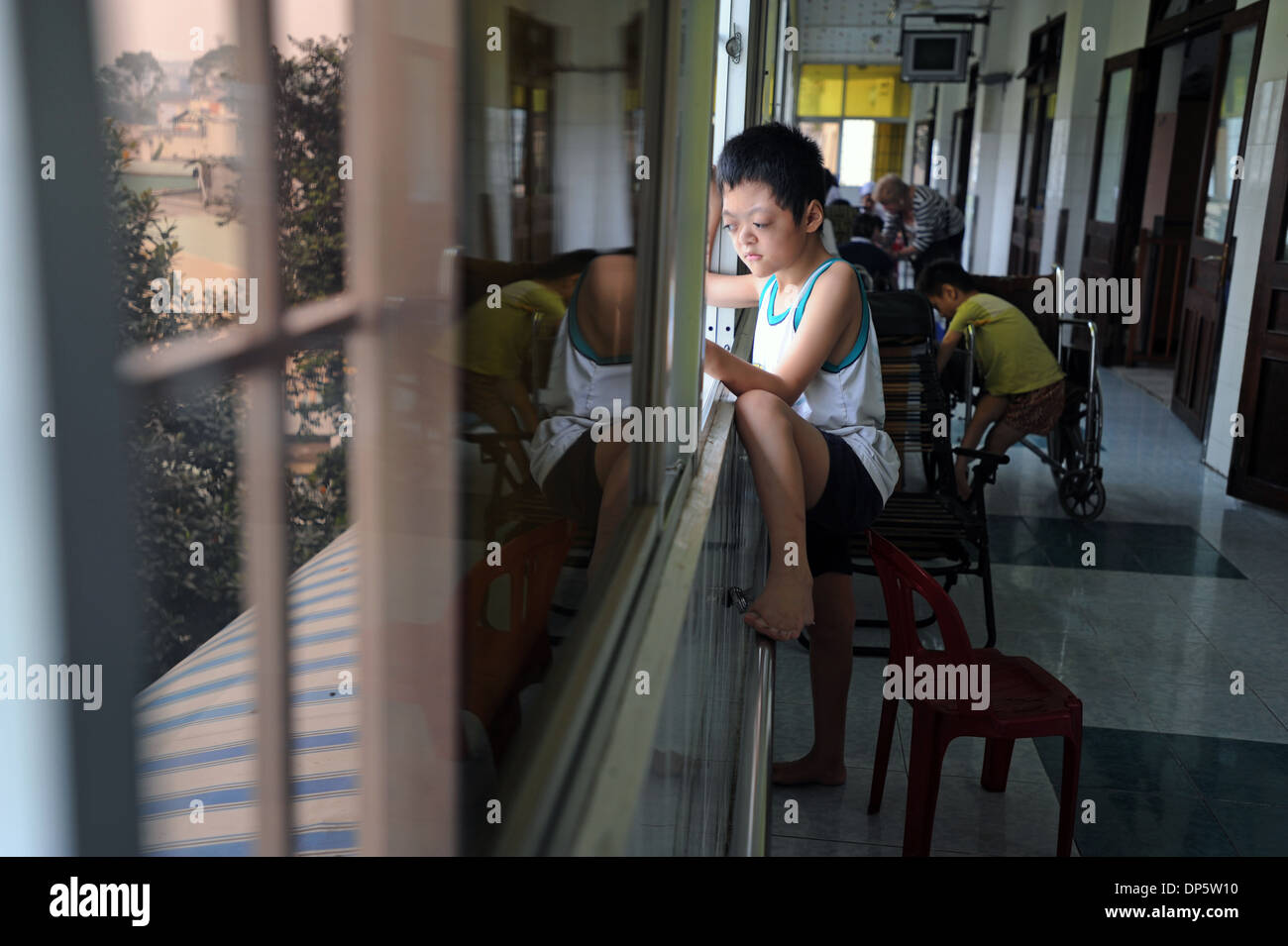 A boy born with protruding eyes and deformed limbs looks out the window ...