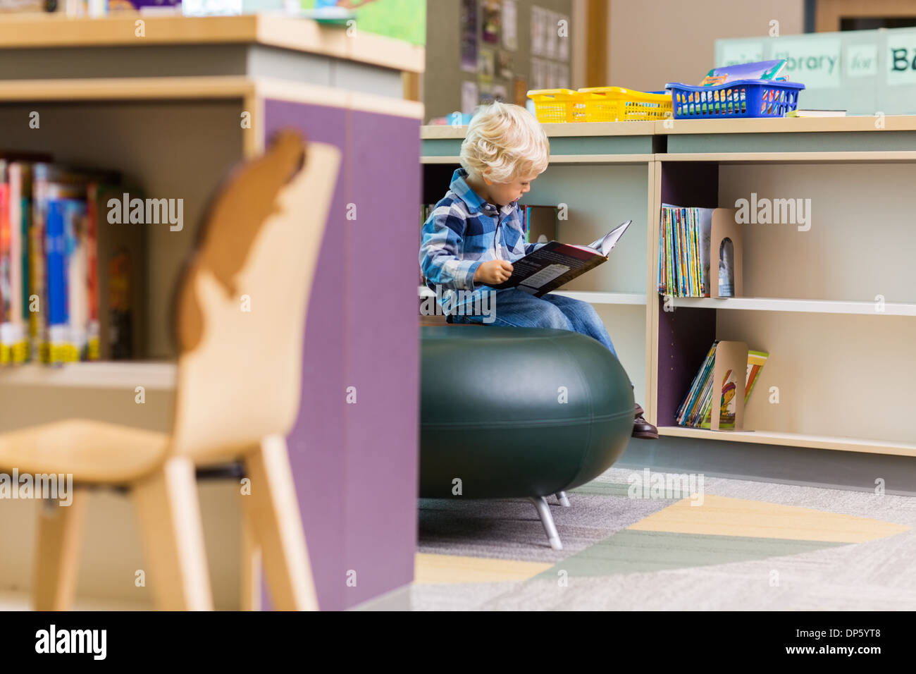 Boy Reading Book In Library Stock Photo - Alamy