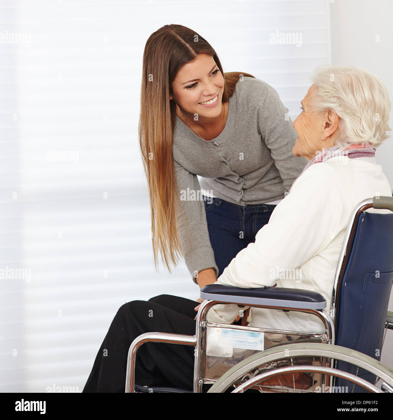 Young woman talking to smiling senior citizen in a wheelchair Stock ...