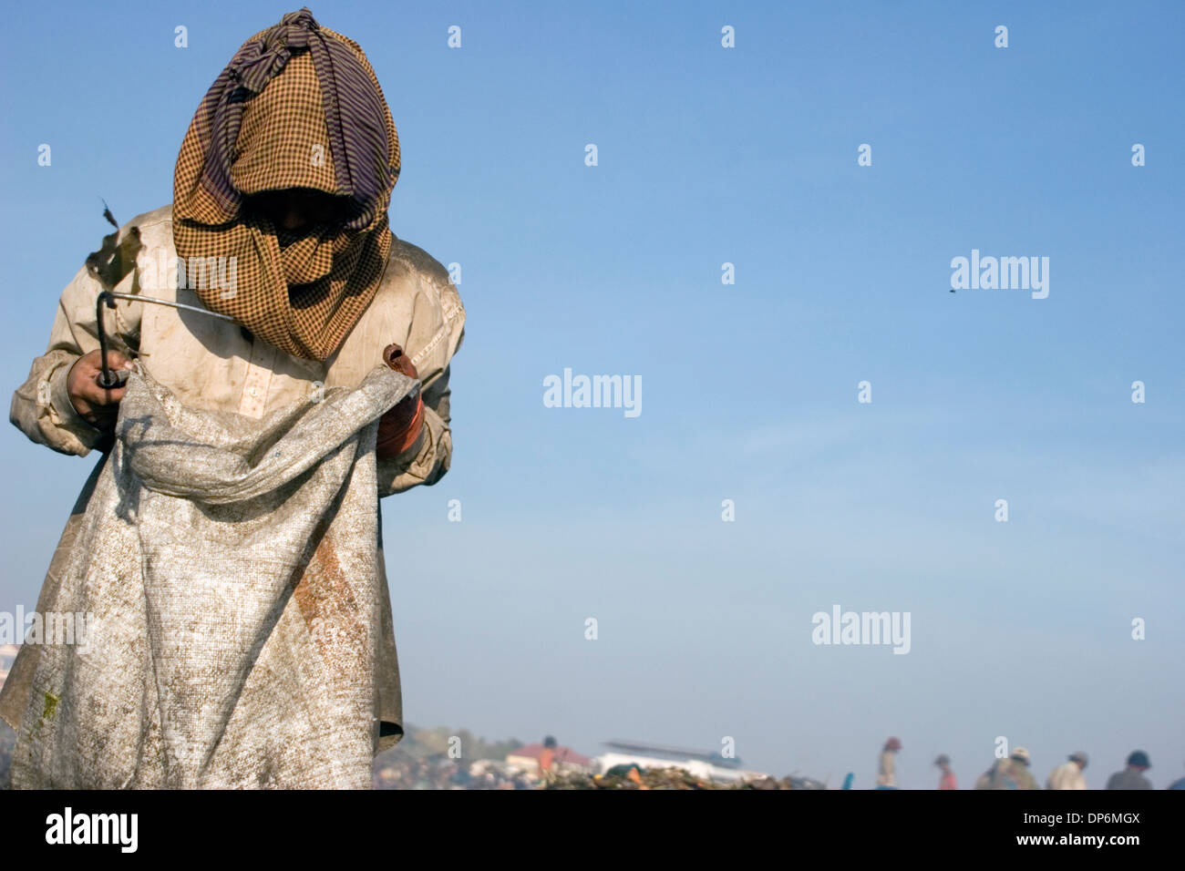 A scavenger man is looking into a sack used to collect garbage at the ...