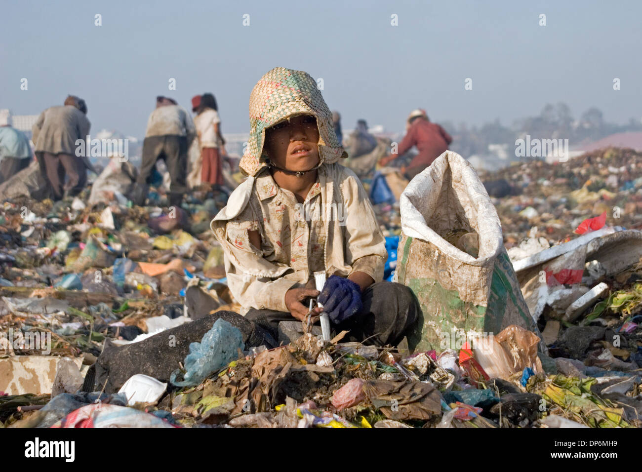 A young girl working as a scavenger is sitting in the toxic and ...