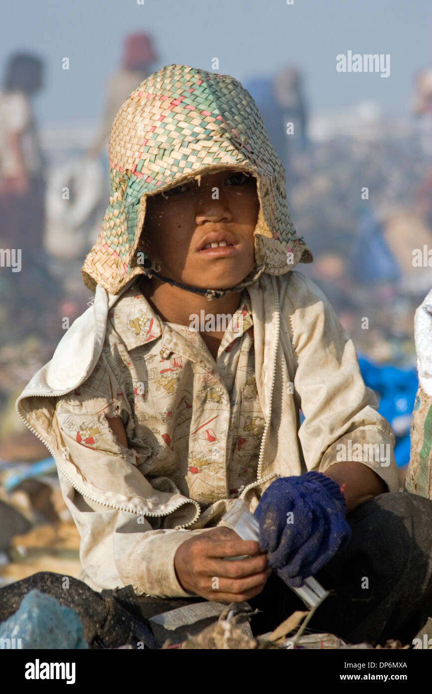 A young girl working as a scavenger is sitting in the toxic and ...