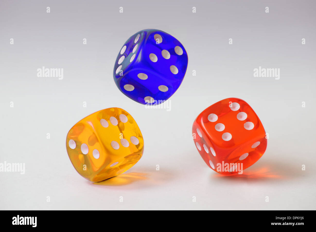 Three coloured plastic dice tumbling on a plain white background Stock ...