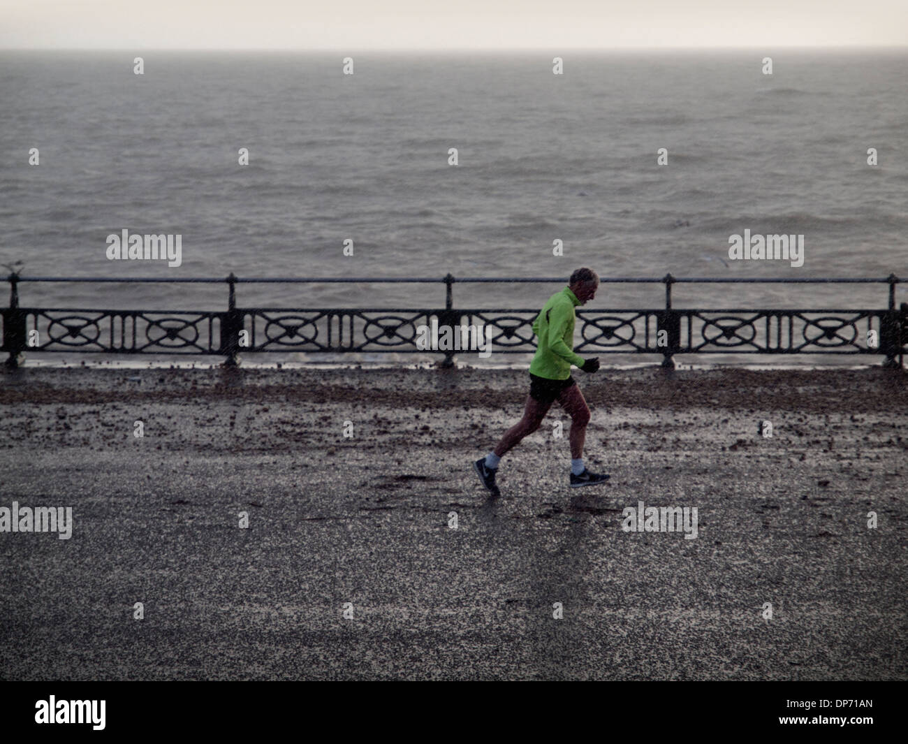 A lone runner jogs along the Hove seafront in rain Stock Photo - Alamy