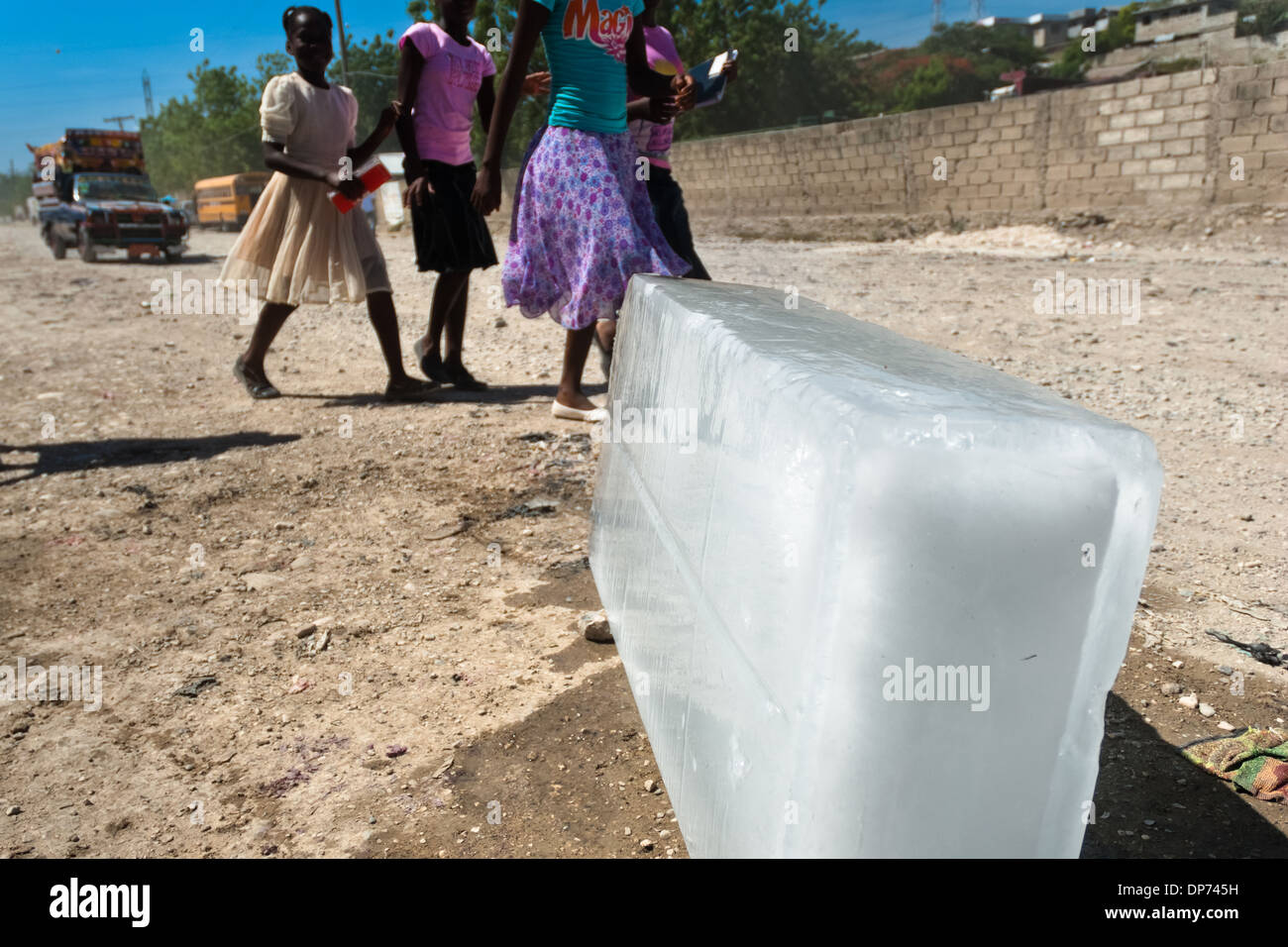 Young Haitian girls walk around a block of ice sold on the street ...
