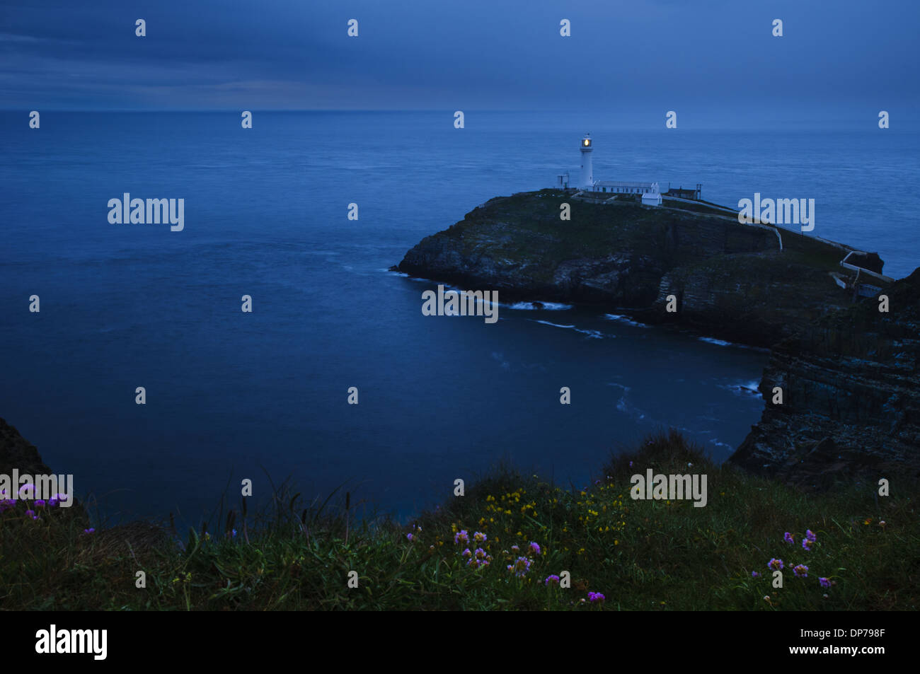 View of coastline and lighthouse at dusk South Stack Lighthouse ...