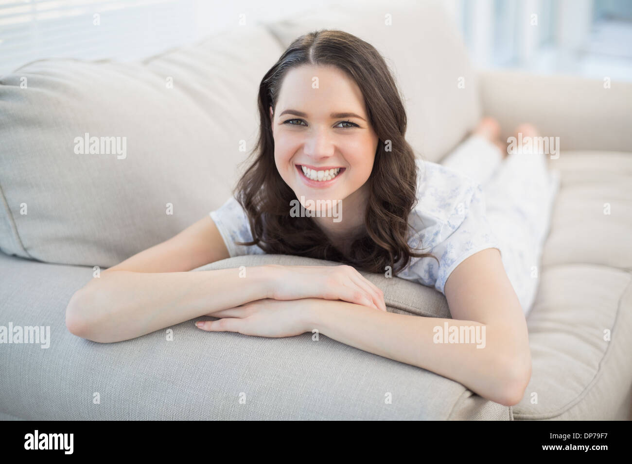 Cheerful pretty woman lying on a cosy couch Stock Photo - Alamy