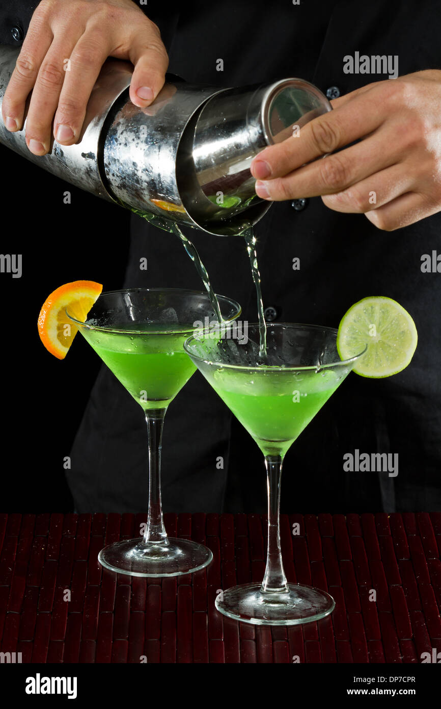 professional bartender pouring two martinis at the same time in a fluid ...