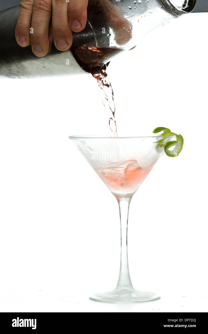 male hands pouring a vodka cocktail in to a chilled martini glass with ...