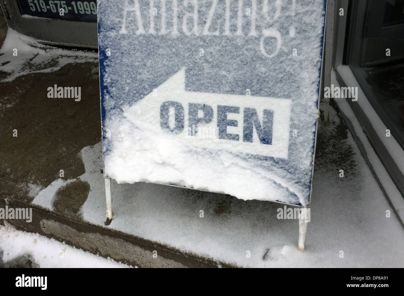 A snow covered open sign in Canada during freezing winter temperatures ...