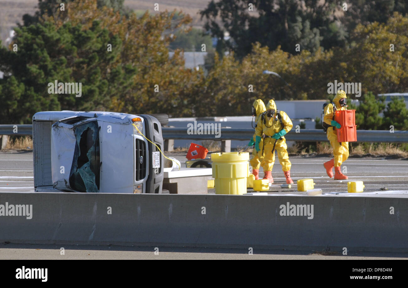 A pickup truck carrying pool chemicals sits on its side after turning ...