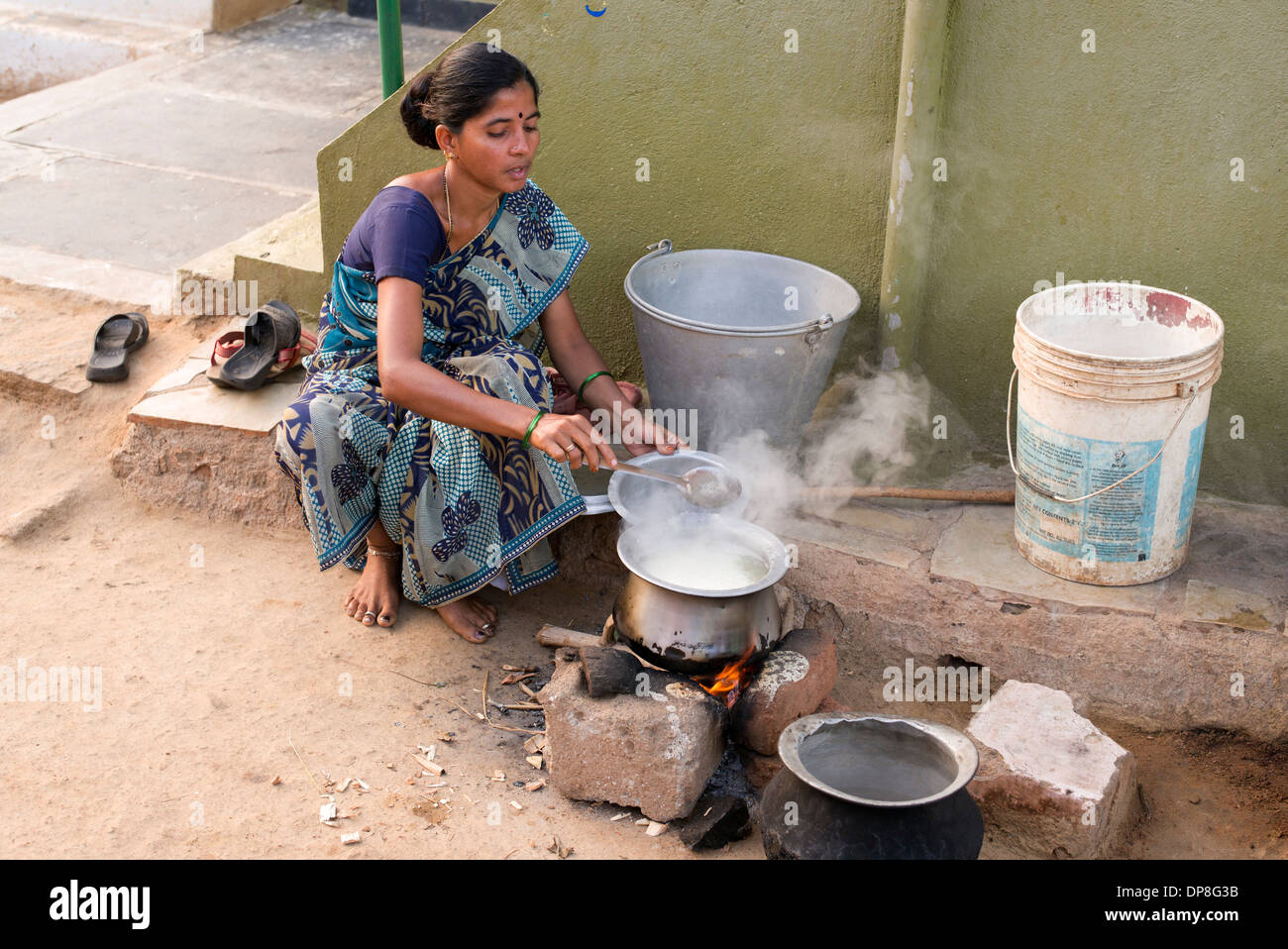 Indian Woman Cooking Rice On An Open Fire Outside Her Home In A Rural