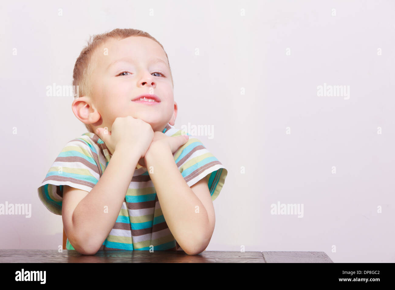 Portrait of blond pensive thoughtful boy child kid at the table ...
