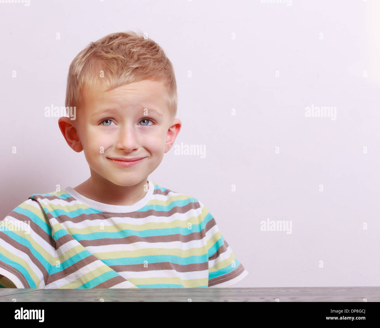 Portrait of blond cute happy smiling boy child kid at the table ...