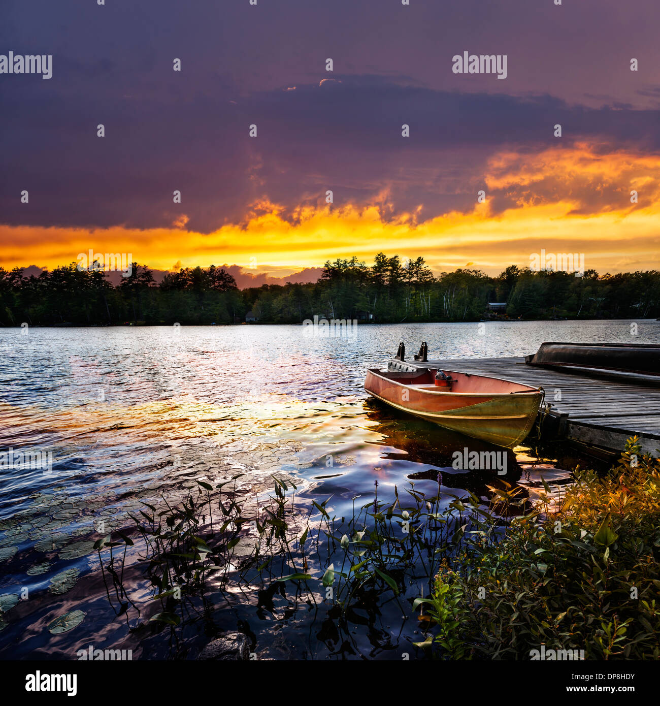 Rowboat tied to dock on beautiful lake with dramatic sunset Stock Photo ...