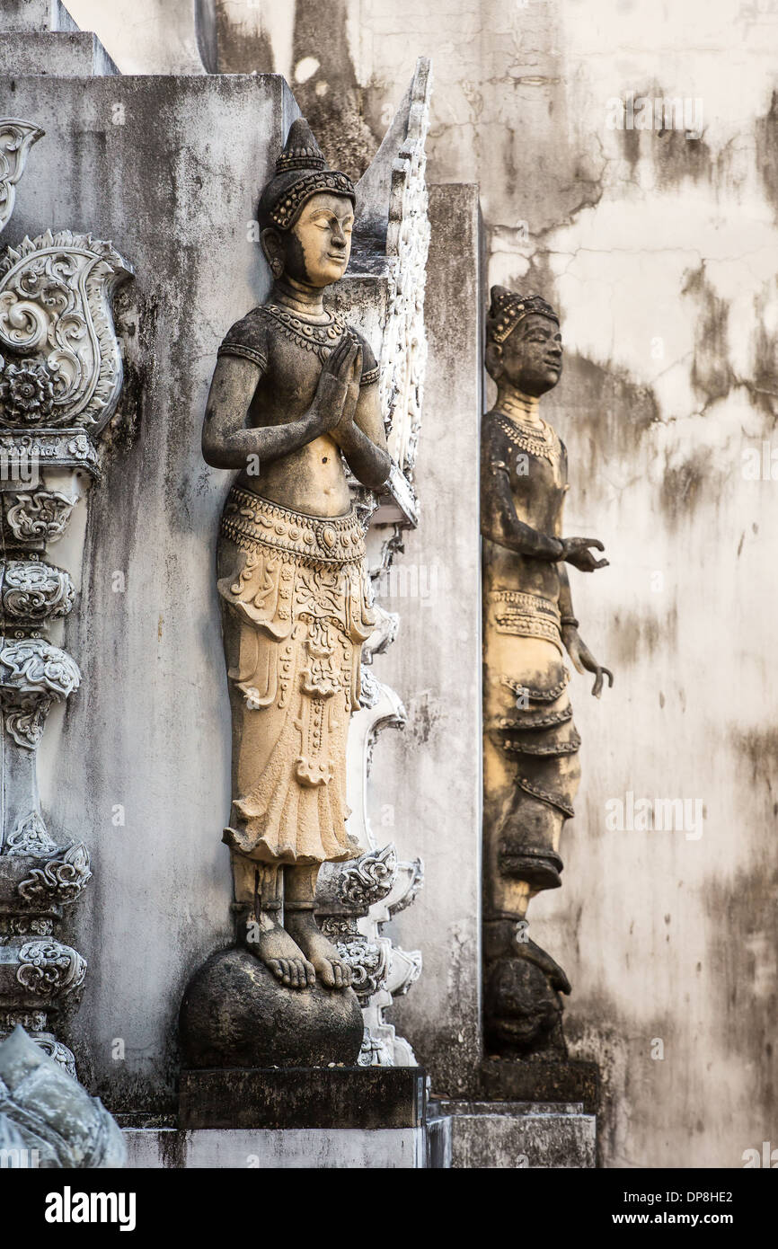 Stone praying women carvings on the wall of the temple in Thailand ...