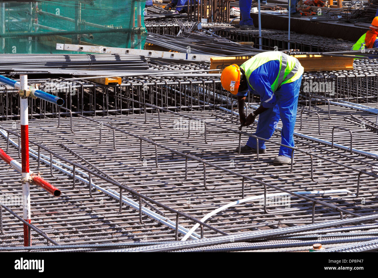 A steel fixer carefully tying reinforced steel bars in position in ...