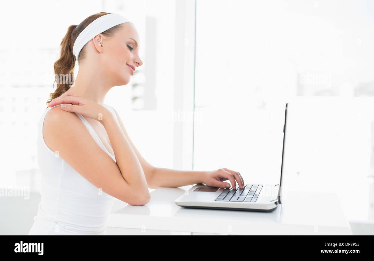Concentrated pretty sportswoman typing on a laptop Stock Photo - Alamy