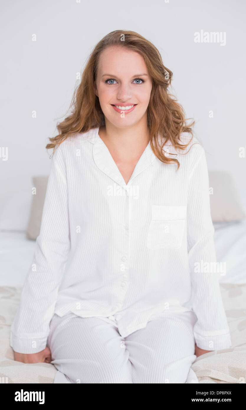 Smiling pretty woman sitting on her bed Stock Photo - Alamy