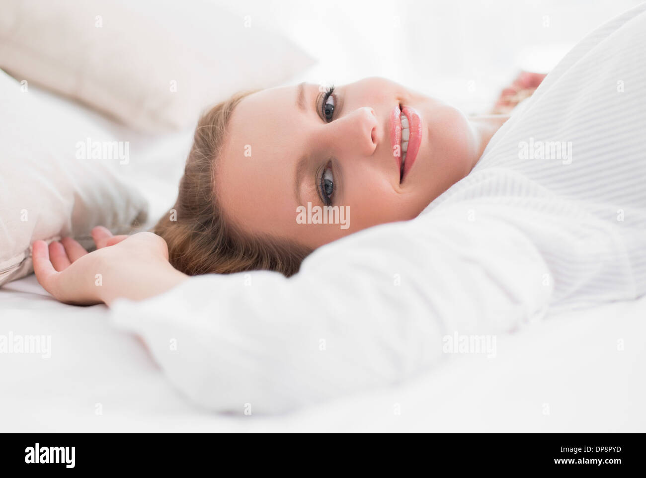 Smiling pretty woman lying on her bed Stock Photo - Alamy