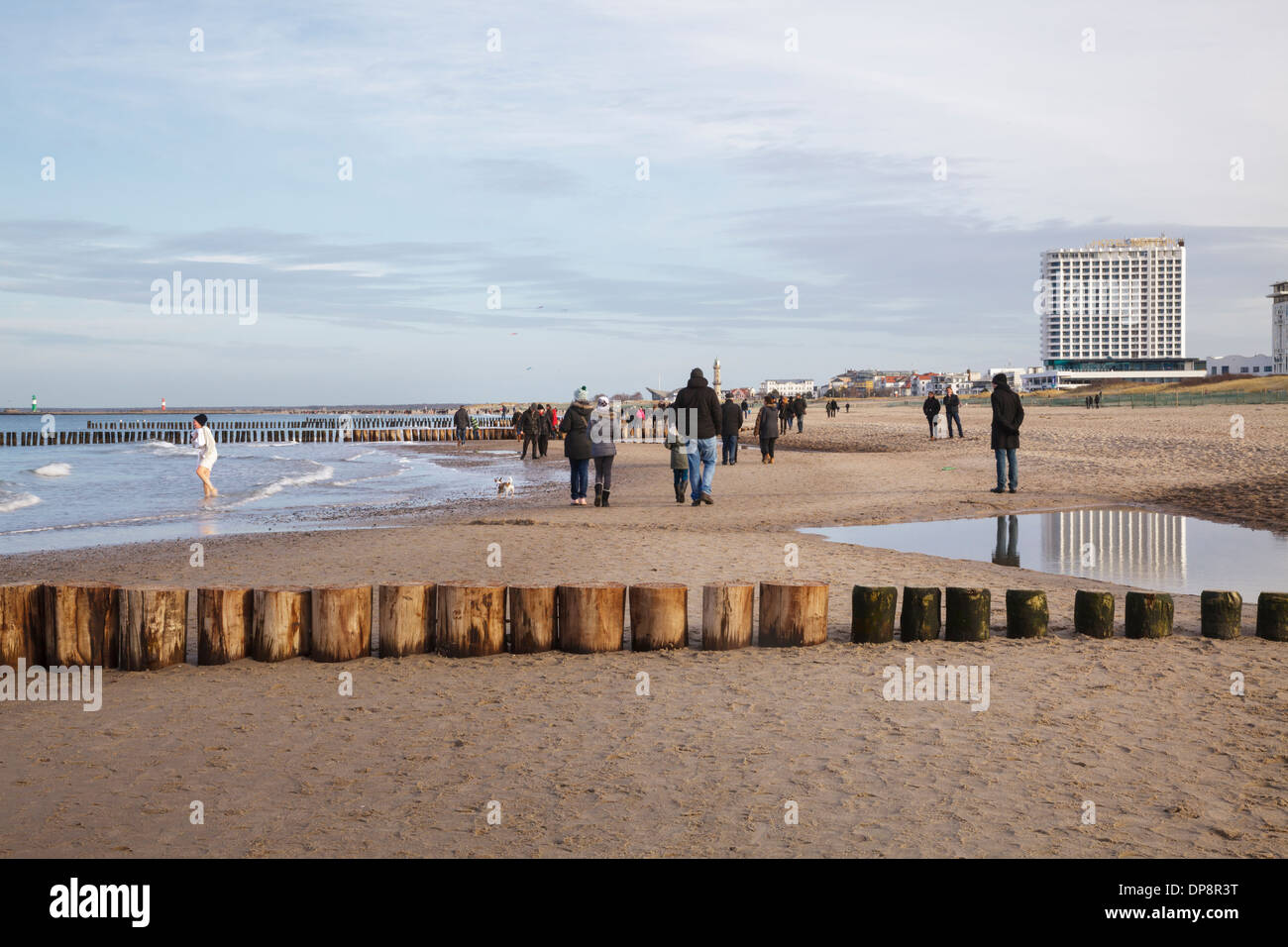 Winter Walkers and a lone bather at the Beach in Warnemuende ...