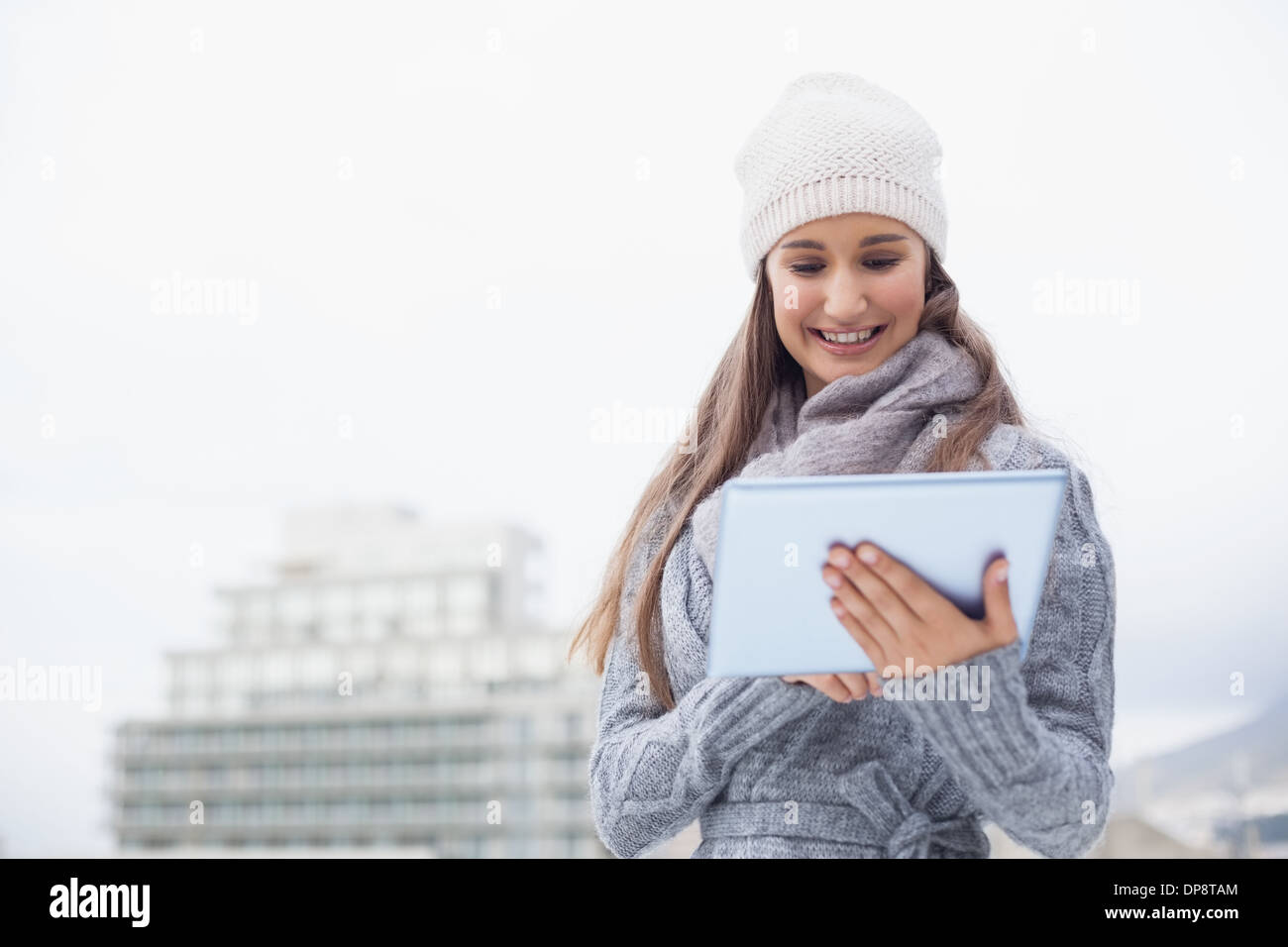 Smiling woman with winter clothes on using her tablet Stock Photo - Alamy