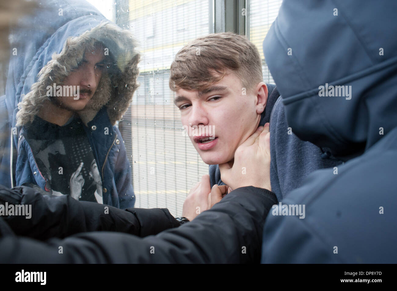 A young man being bullied at a bus stop by a group of teenage boys ...