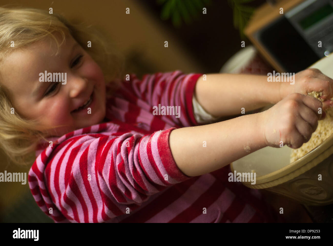 Smiling little girl crumbling pastry into a mixing bowl Stock Photo - Alamy