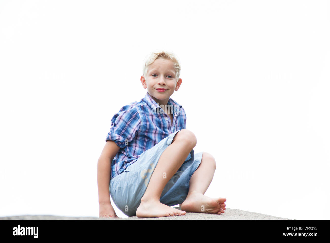 a young boy sitting on a stone Stock Photo - Alamy