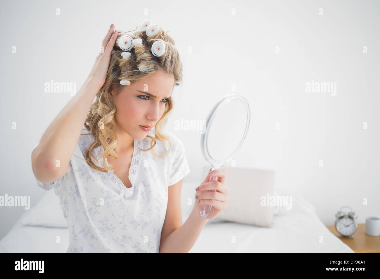 Frowning gorgeous blonde wearing hair curlers posing Stock Photo - Alamy