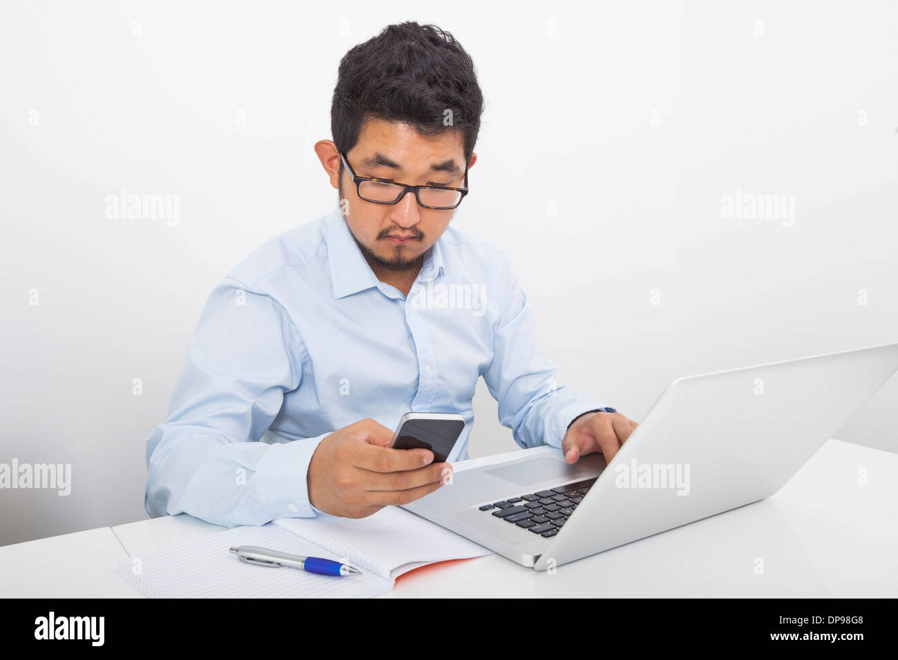 Young businessman using cell phone while working at desk in office ...