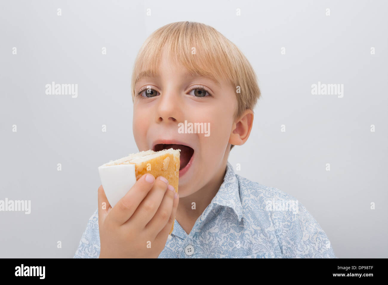 Portrait of cute boy eating cake slice against gray background Stock ...