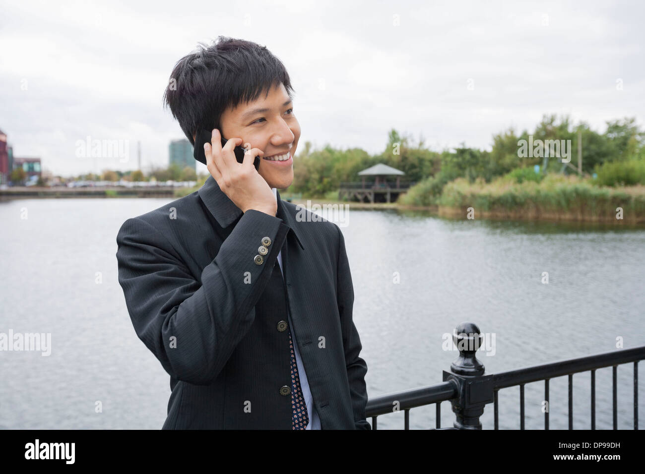 Happy mid adult businessman using cell phone at bridge railing Stock ...