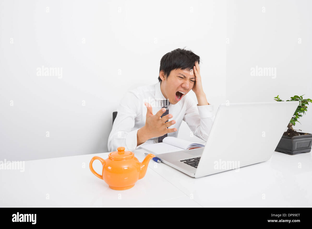 Mid adult businessman screaming with laptop on desk in office Stock ...