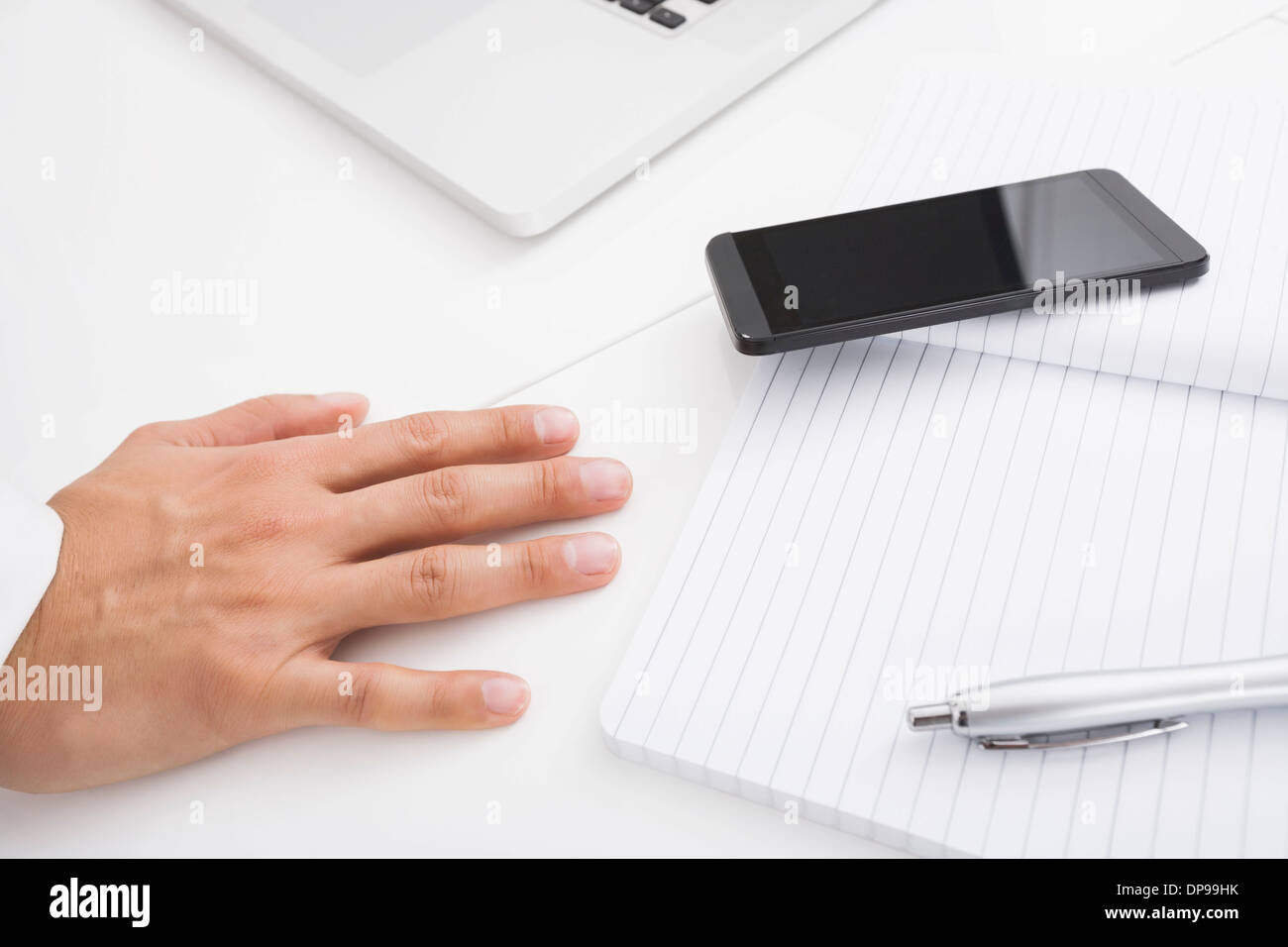 Businessman's hand on desk by cell phone pen and book Stock Photo - Alamy