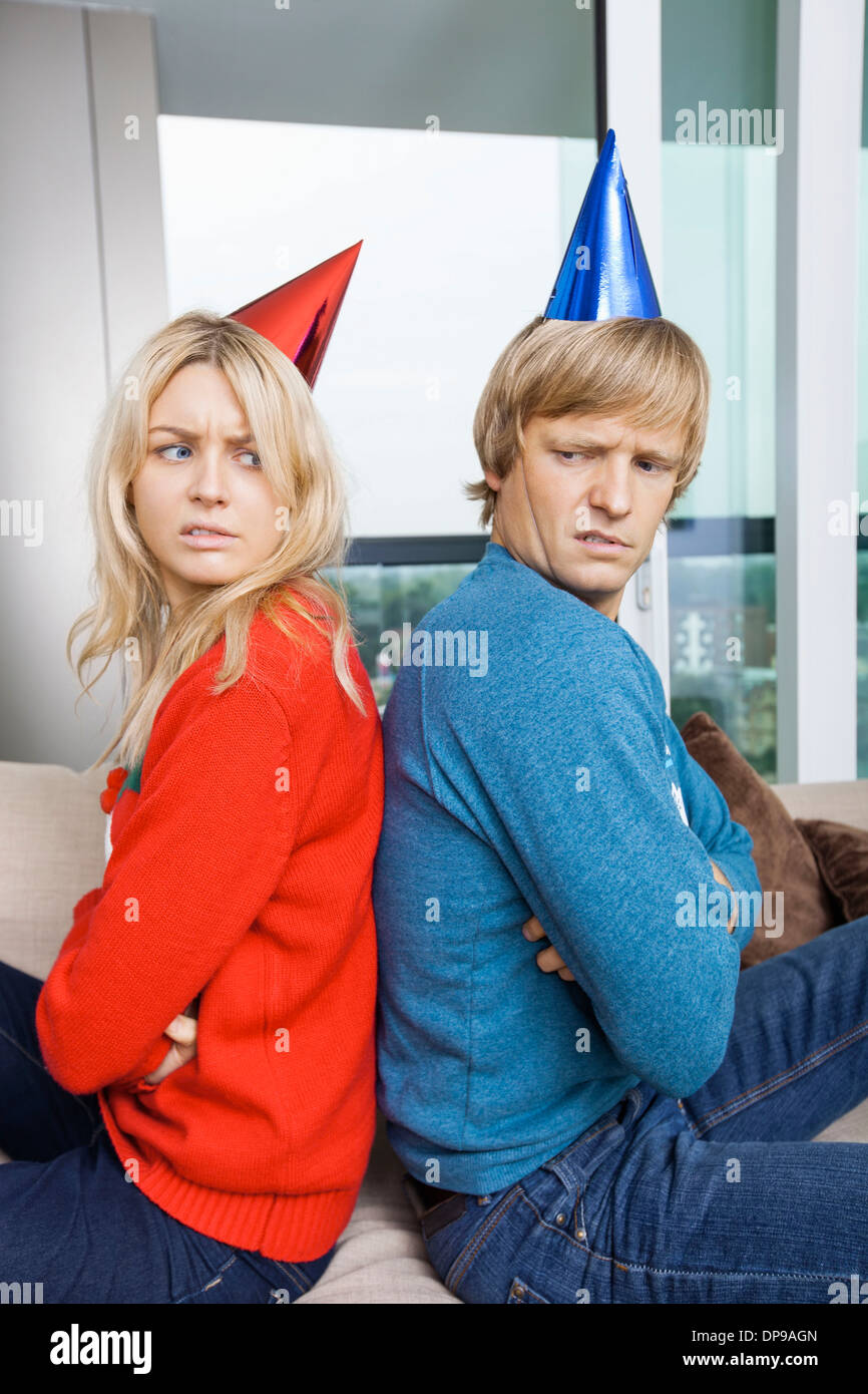 Side view of annoyed couple in Christmas sweaters and party hats ...