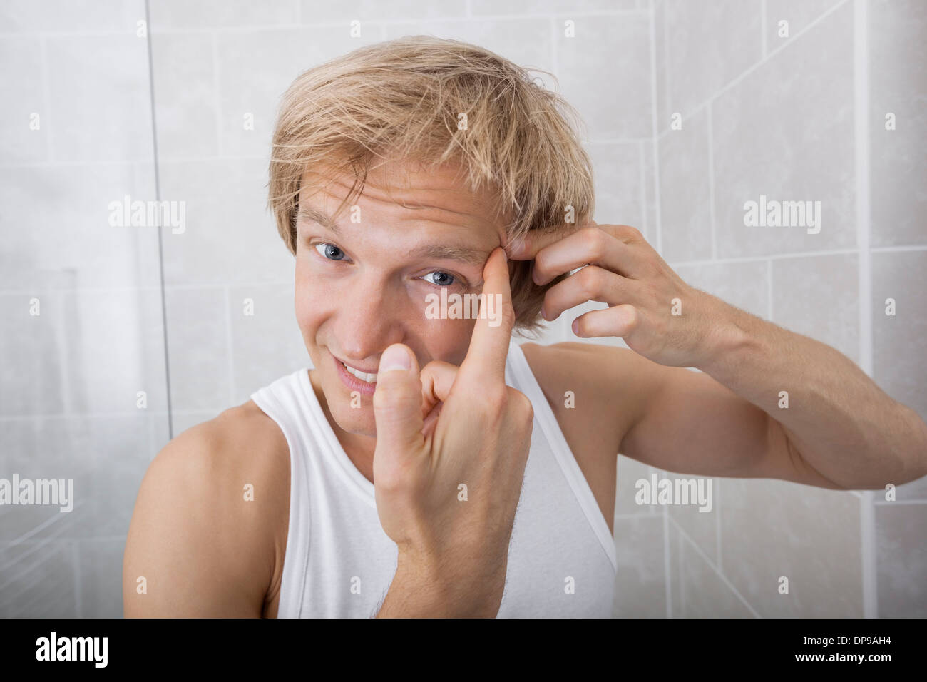 Portrait of man squeezing pimple on his forehead in bathroom Stock ...
