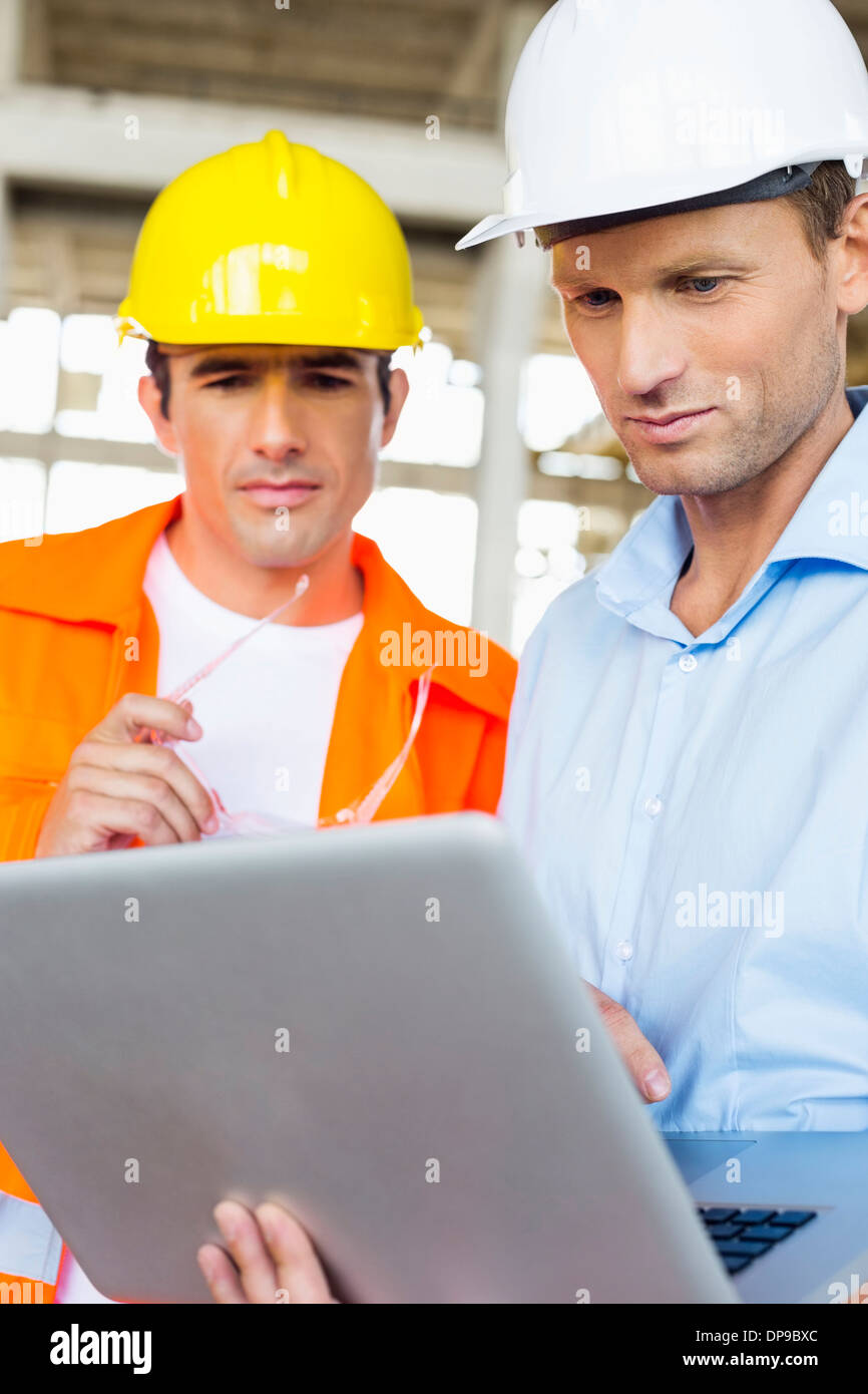 Male architects working on laptop at construction site Stock Photo - Alamy