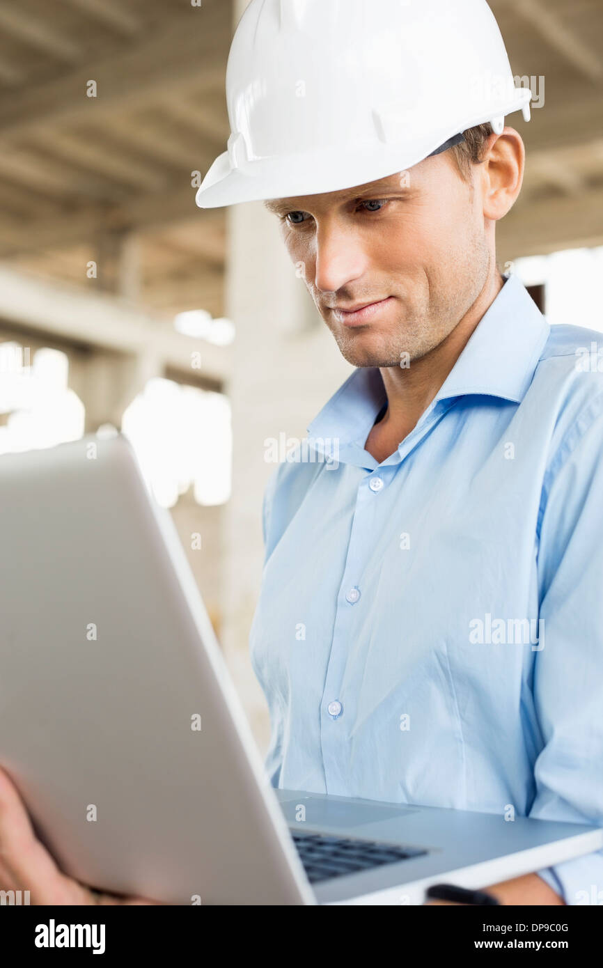 Confident male architect using laptop at construction site Stock Photo ...