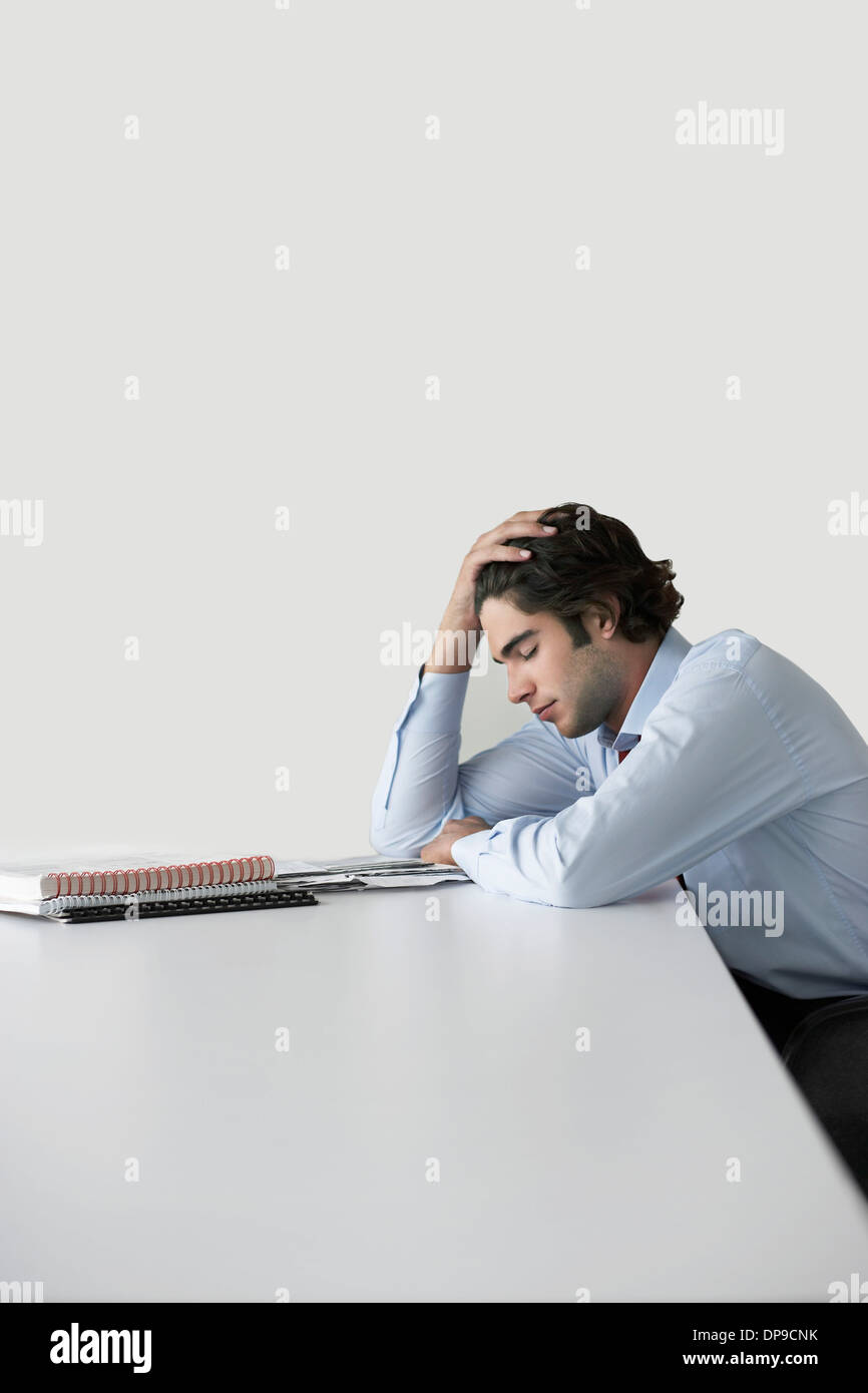 Sad young businessman leaning on desk in office Stock Photo - Alamy