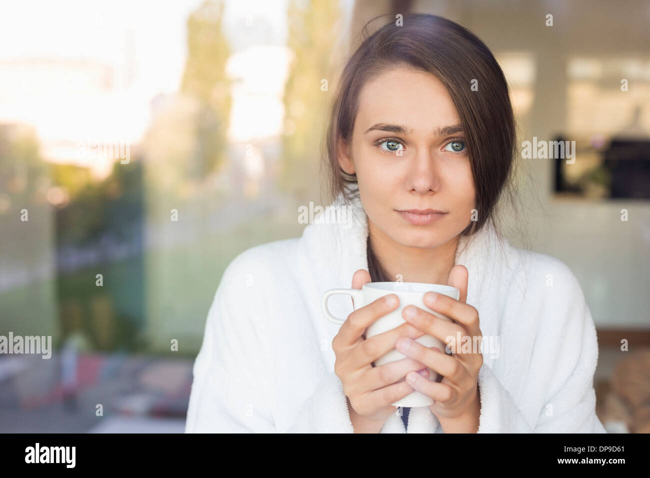 Sick young woman holding coffee mug at home Stock Photo - Alamy