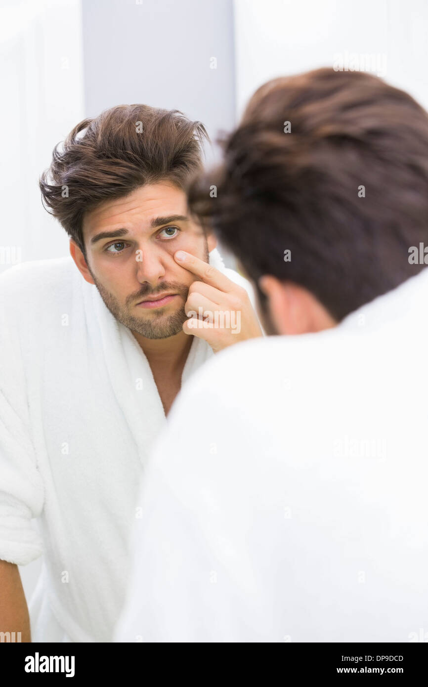 Reflection of ill man examining eyes in mirror Stock Photo - Alamy