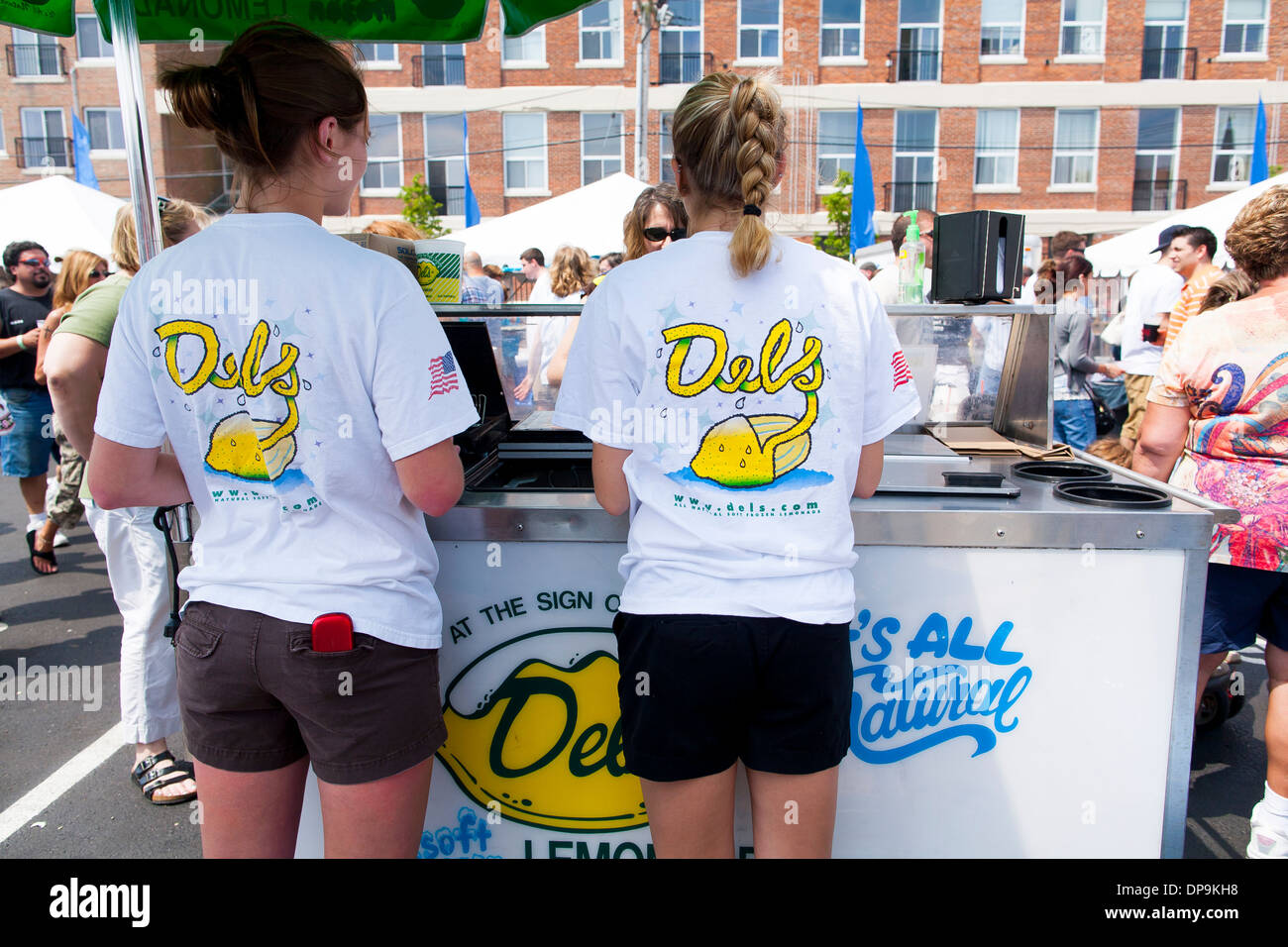 Servers at a cart selling Del's lemonade standing under an umbrella at ...