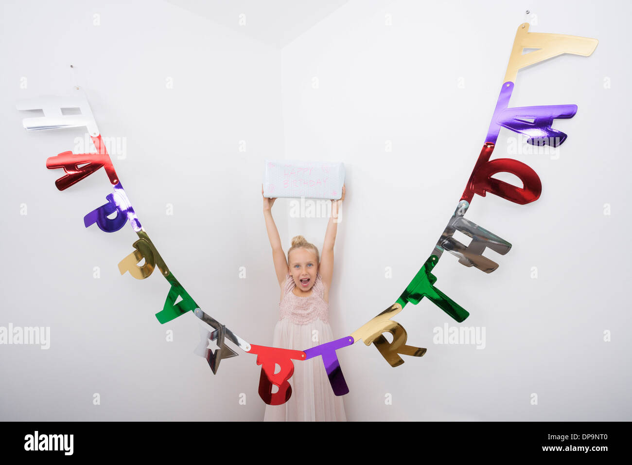 Portrait of girl with mouth open holding birthday gift over head Stock ...