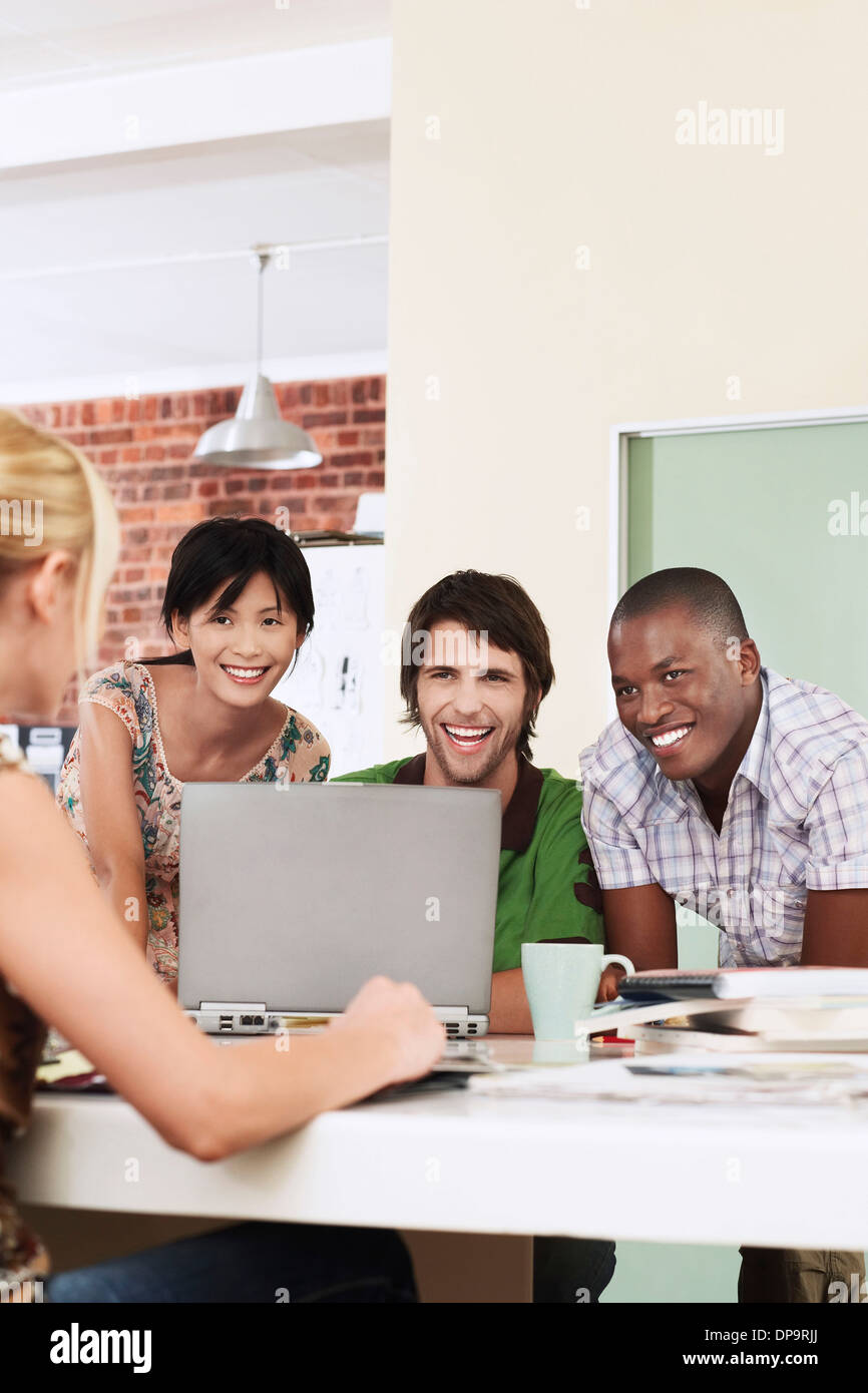 Four people having meeting around laptop laughing Stock Photo - Alamy