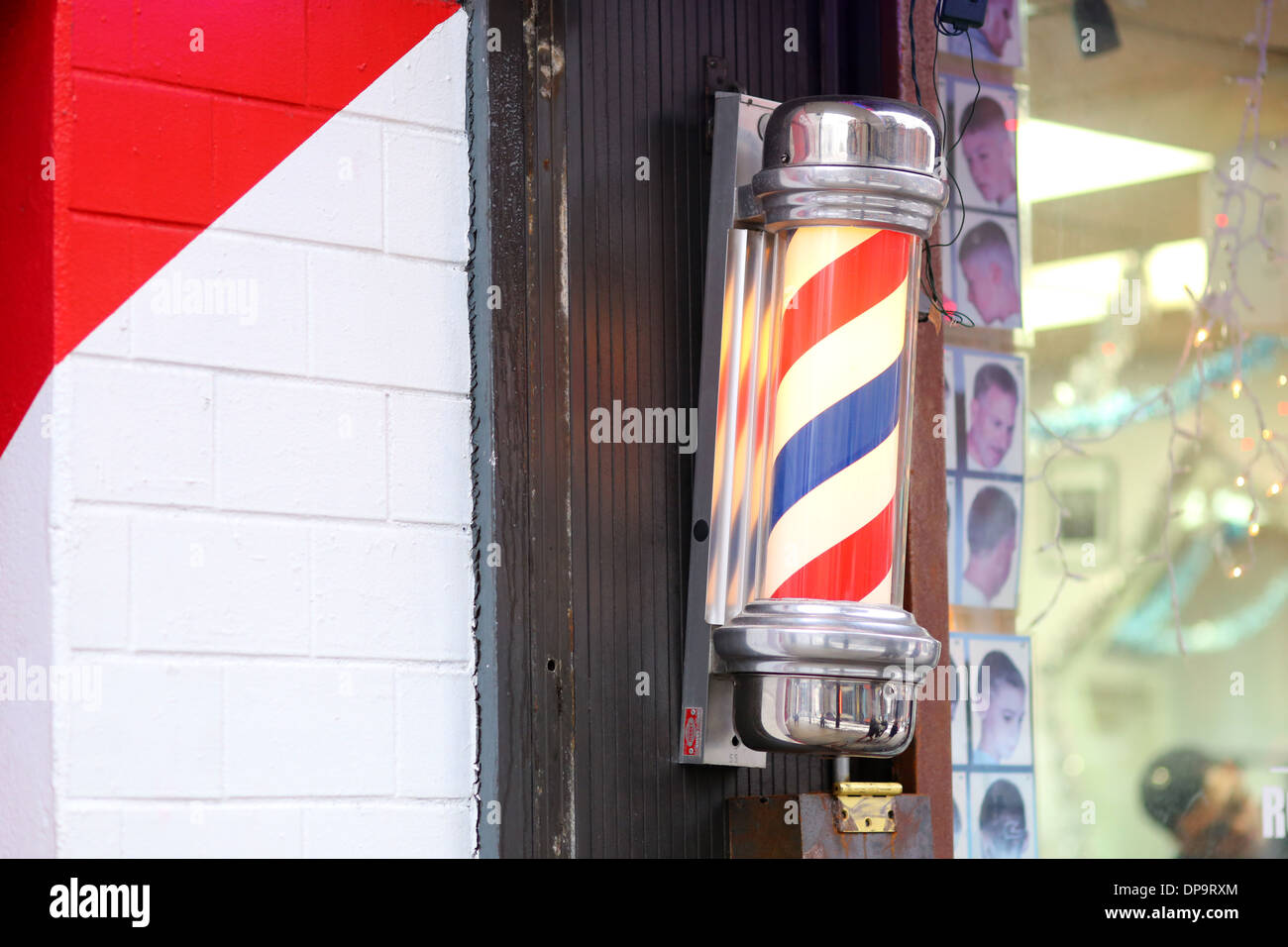 A red white and blue stripped spinning barber pole advertising a barber ...