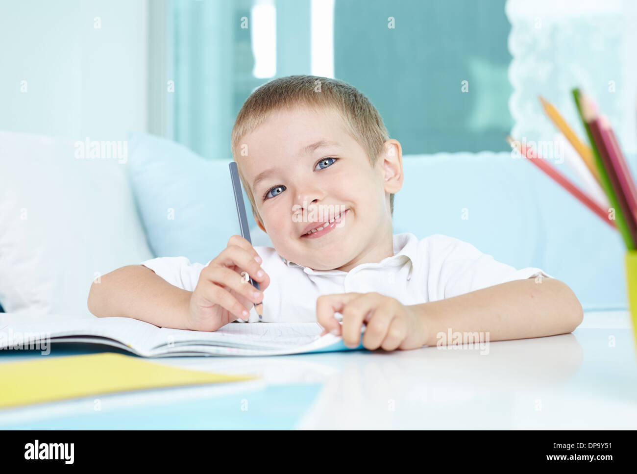 Smiling boy looking at camera while drawing Stock Photo - Alamy