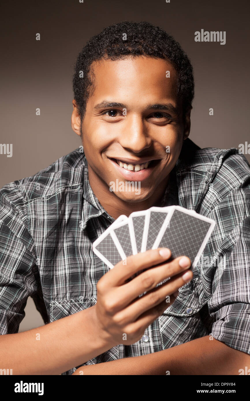 smiling dark-skinned young man holding playing cards Stock Photo - Alamy