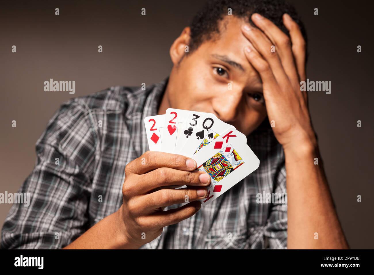 young dark-skinned man shows bad poker cards Stock Photo - Alamy